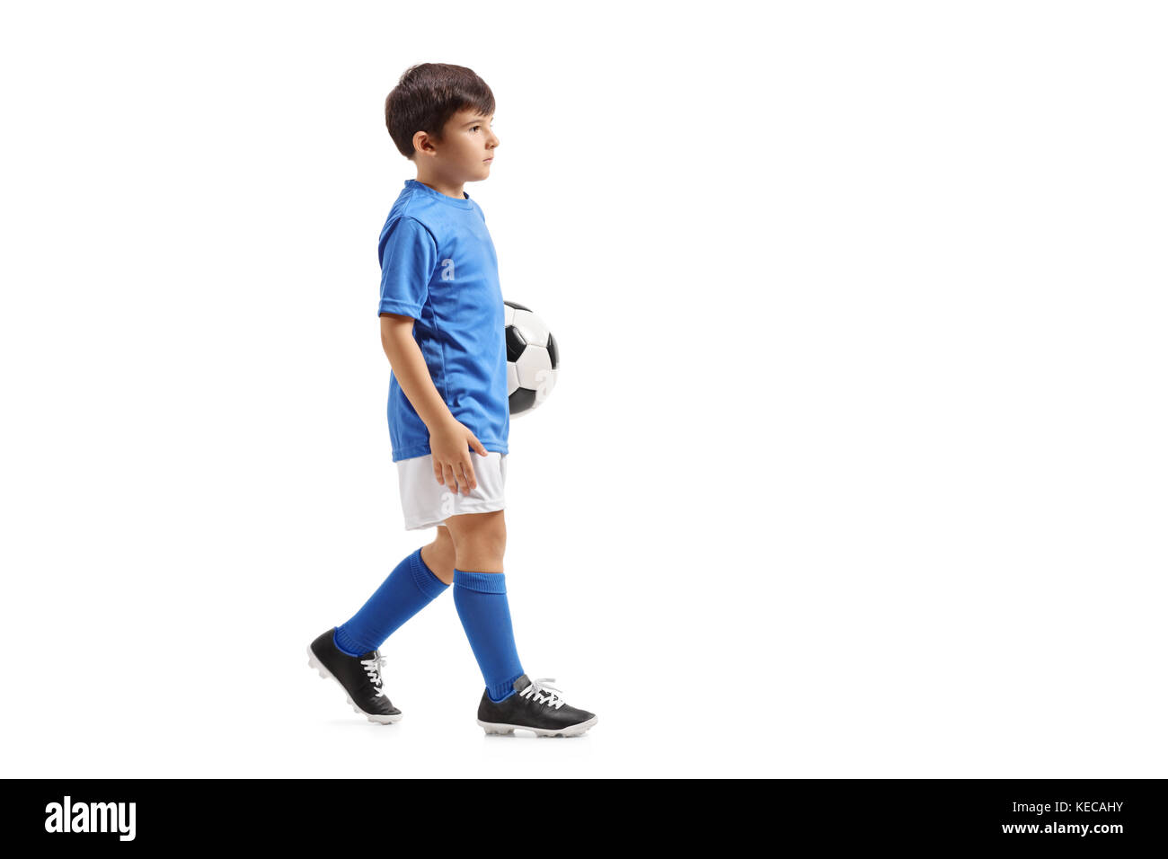 Full length profile shot of a little soccer player holding a football ...