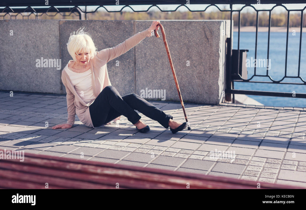 Elderly lady getting up after falling down in the street Stock Photo ...