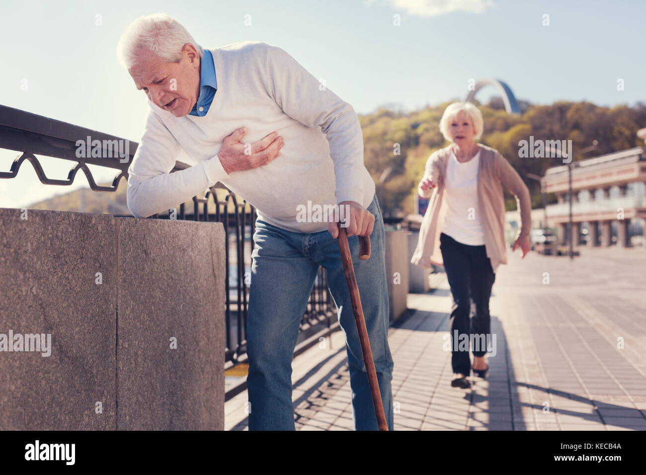 Senior woman running to help a man having heart attack Stock Photo - Alamy