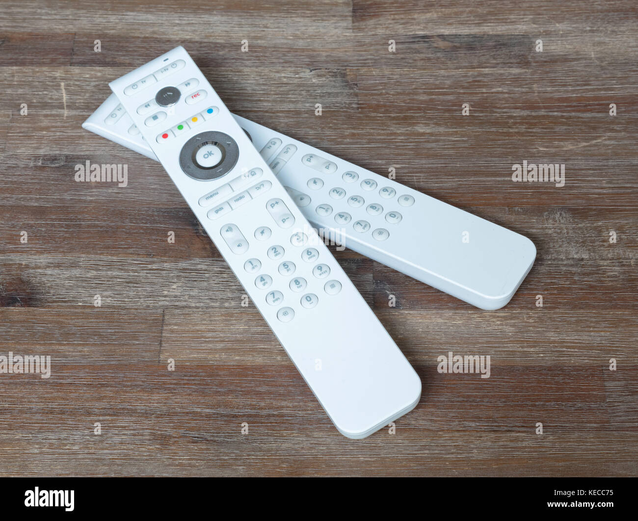 Two white remotes on a wooden table Stock Photo - Alamy