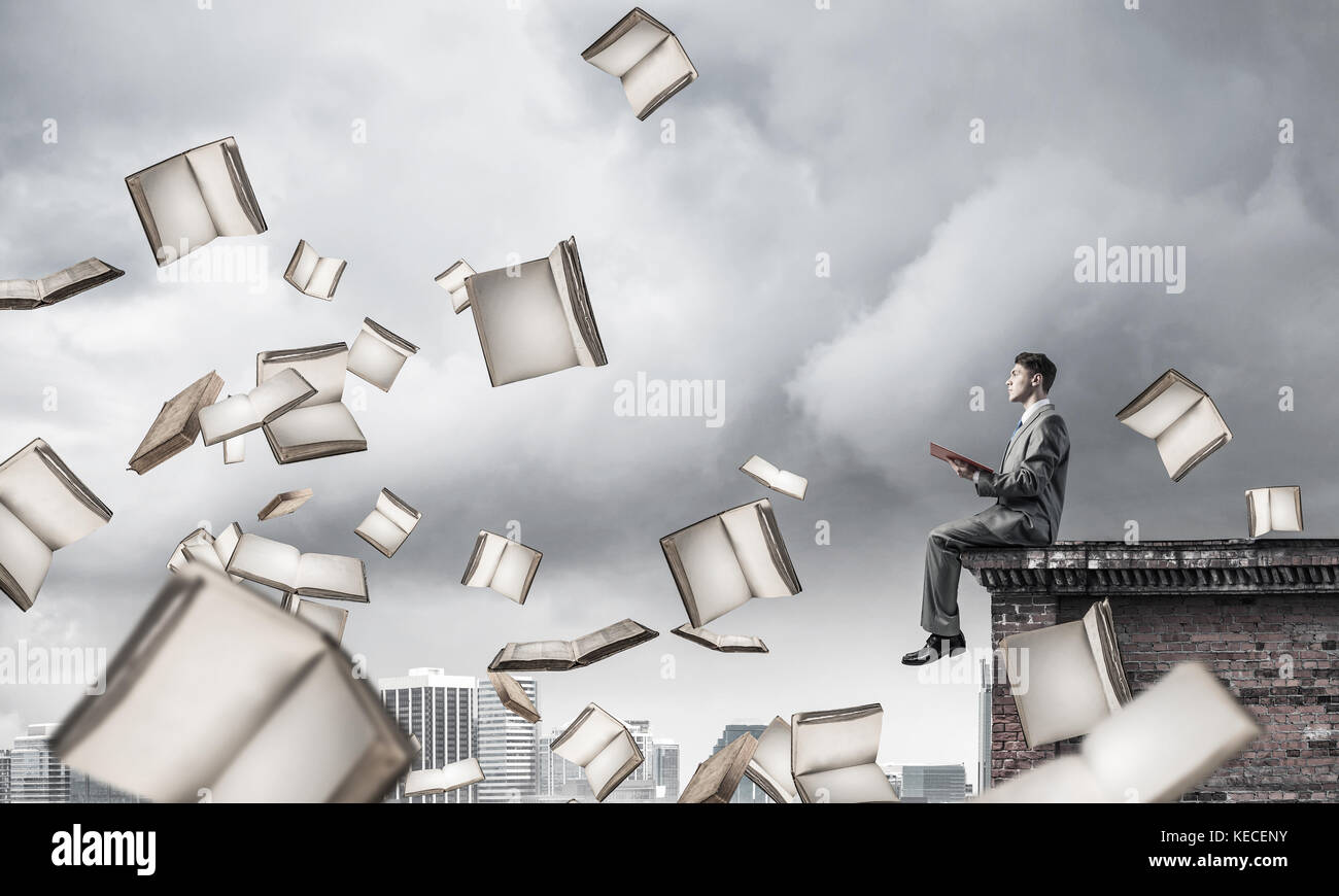 Man on roof reading book and many of them flying in air Stock Photo - Alamy