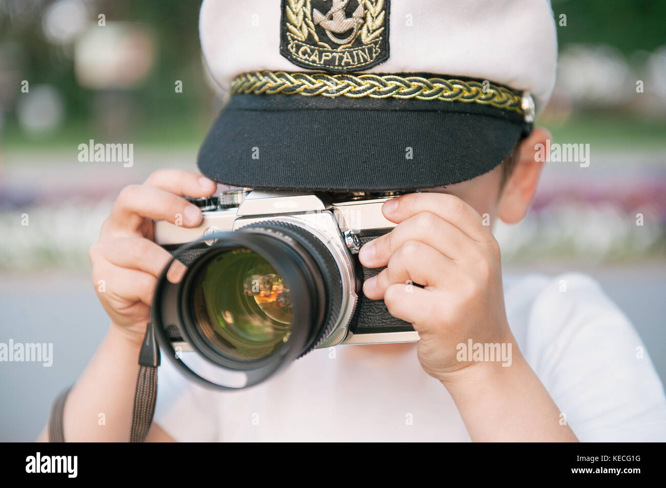 child wearing captain hat takes a picture using vintage film camera ...