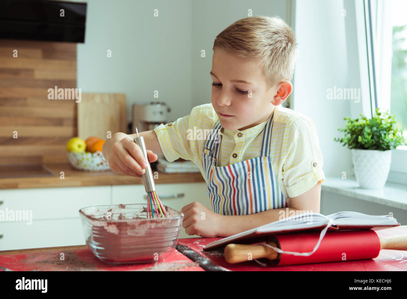 Portrait of young boy preparing chocolate cookies at modert kitchen ...