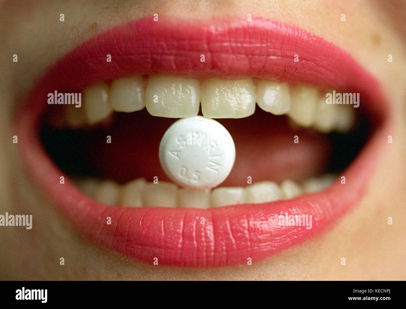 Close-up of woman with aspirin tablet between her teeth. The famous ...