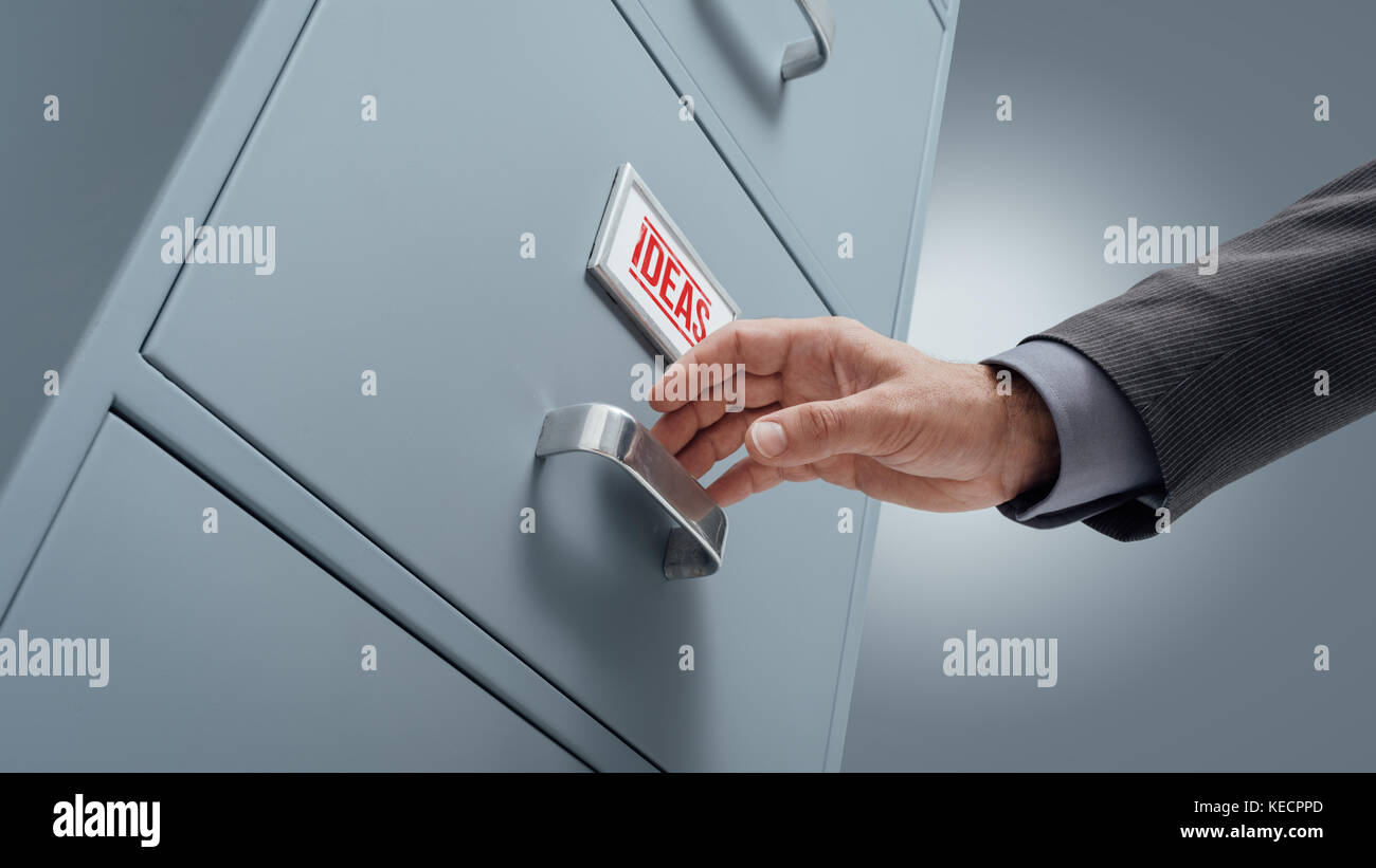 Businessman searching files in a filing cabinet, he is opening a drawer ...