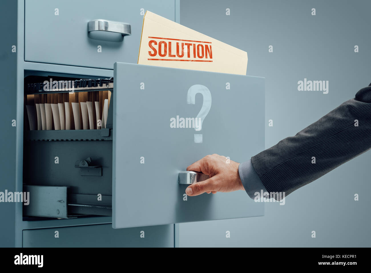 Businessman finding a business solution file in a filing cabinet drawer ...