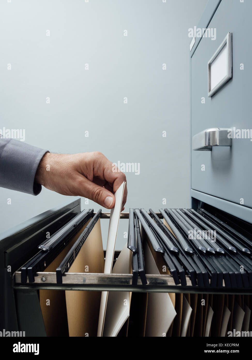 Office clerk searching for files into a filing cabinet drawer close up ...