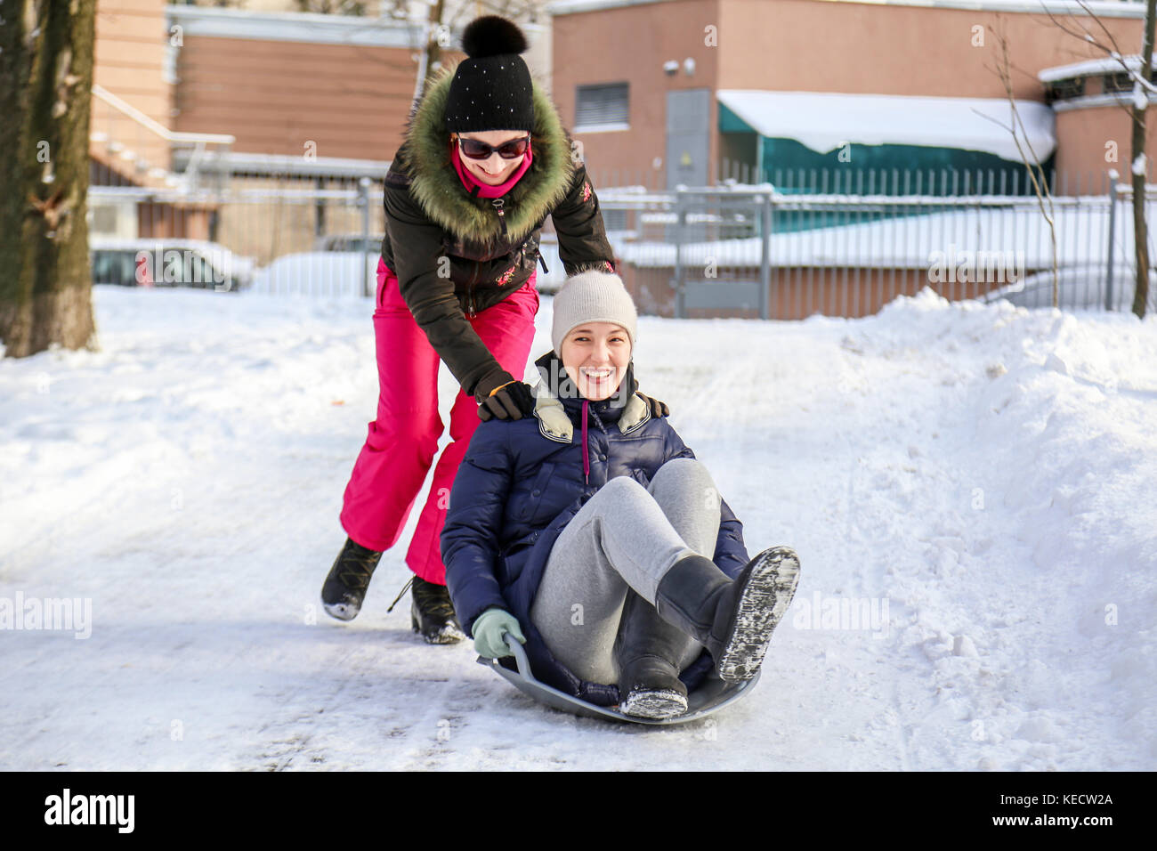 Two beautiful caucasian girls laughing and having fun riding a saucer ...