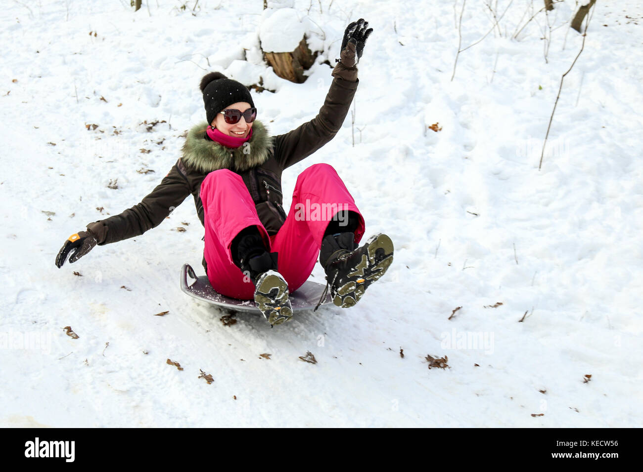 Beautiful caucasian girl laughing and having fun riding a saucer sled ...