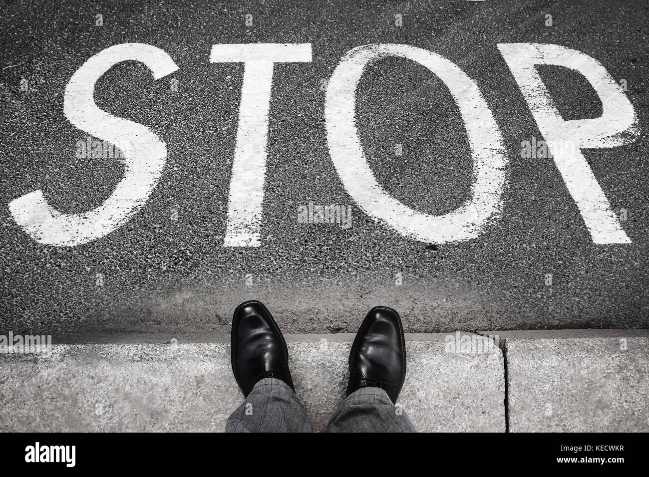 Feet of a man in black shining shoes standing opposite stop road ...