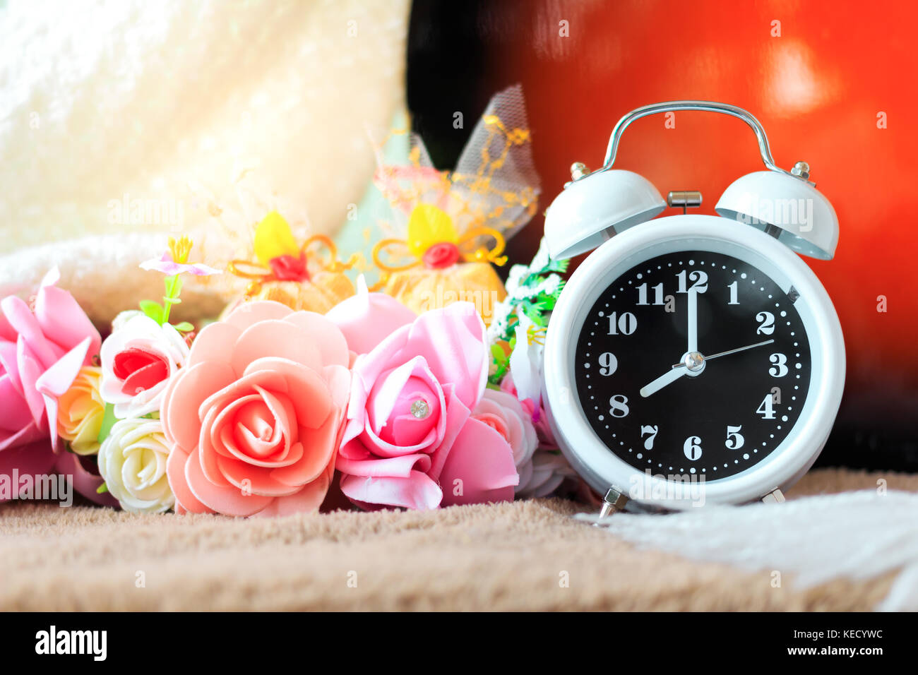 Small alarm clock with beautiful flowers on table Stock Photo - Alamy