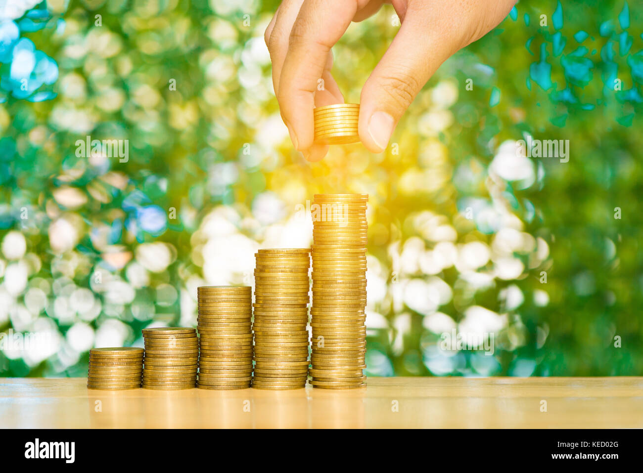 Woman hand put coin on step of coins stacks and gold coin money in the ...