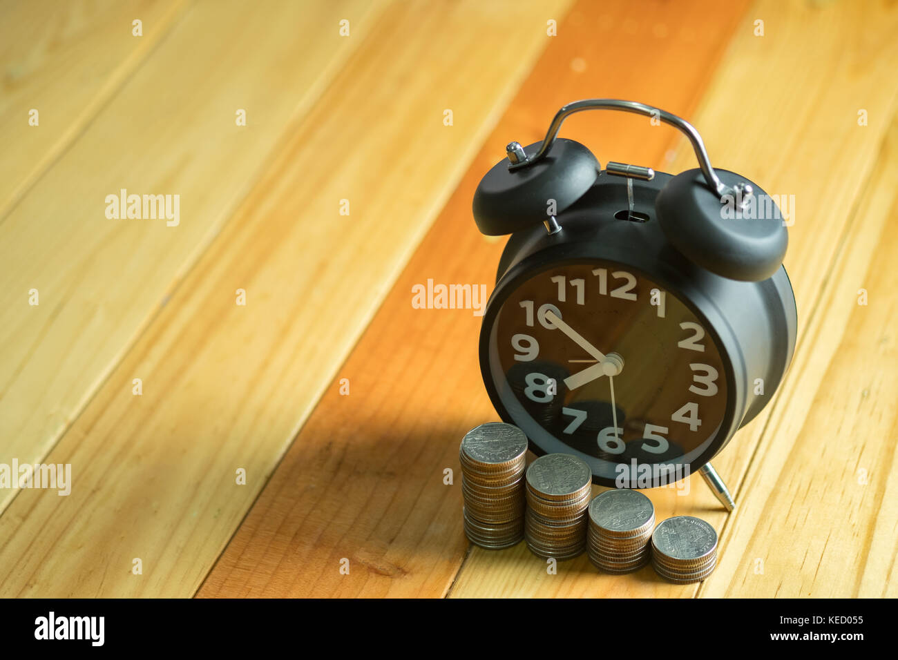Alarm clock and step of coins stacks on working table, time for savings ...