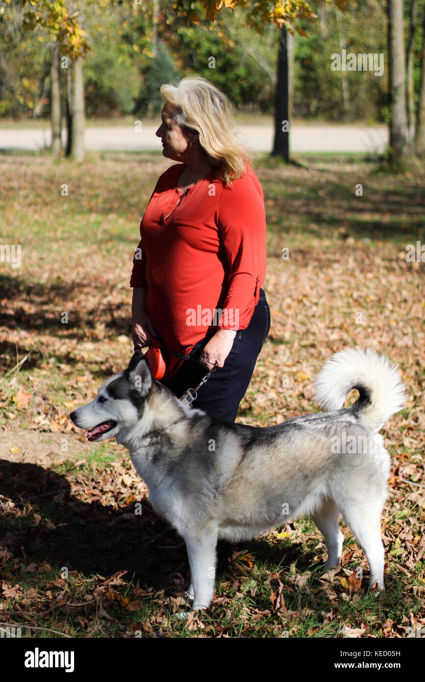 A senior citizen woman stands with her Siberian Husky dog outside in ...