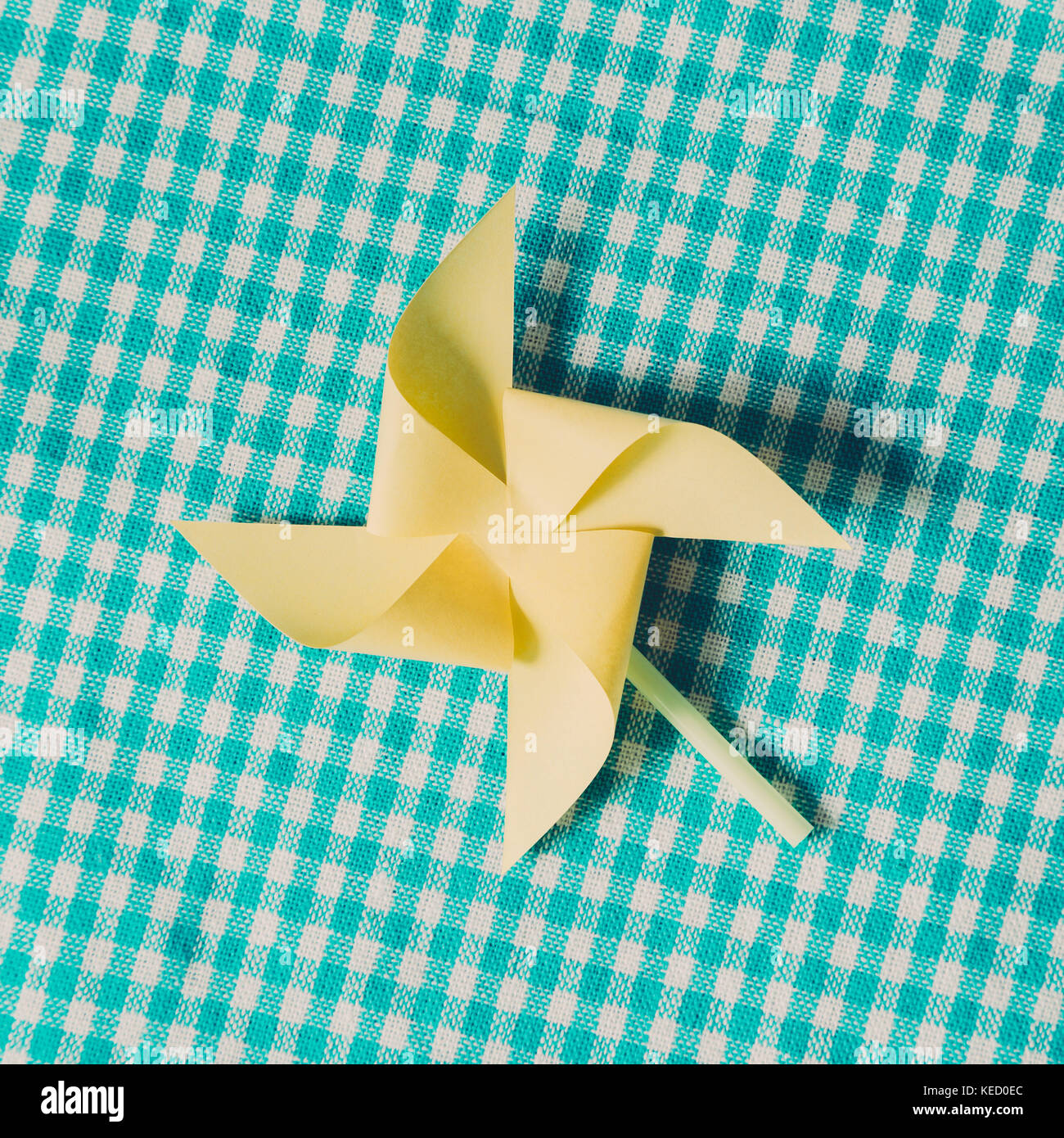 Yellow paper pinwheel on blue check fabric background Stock Photo - Alamy