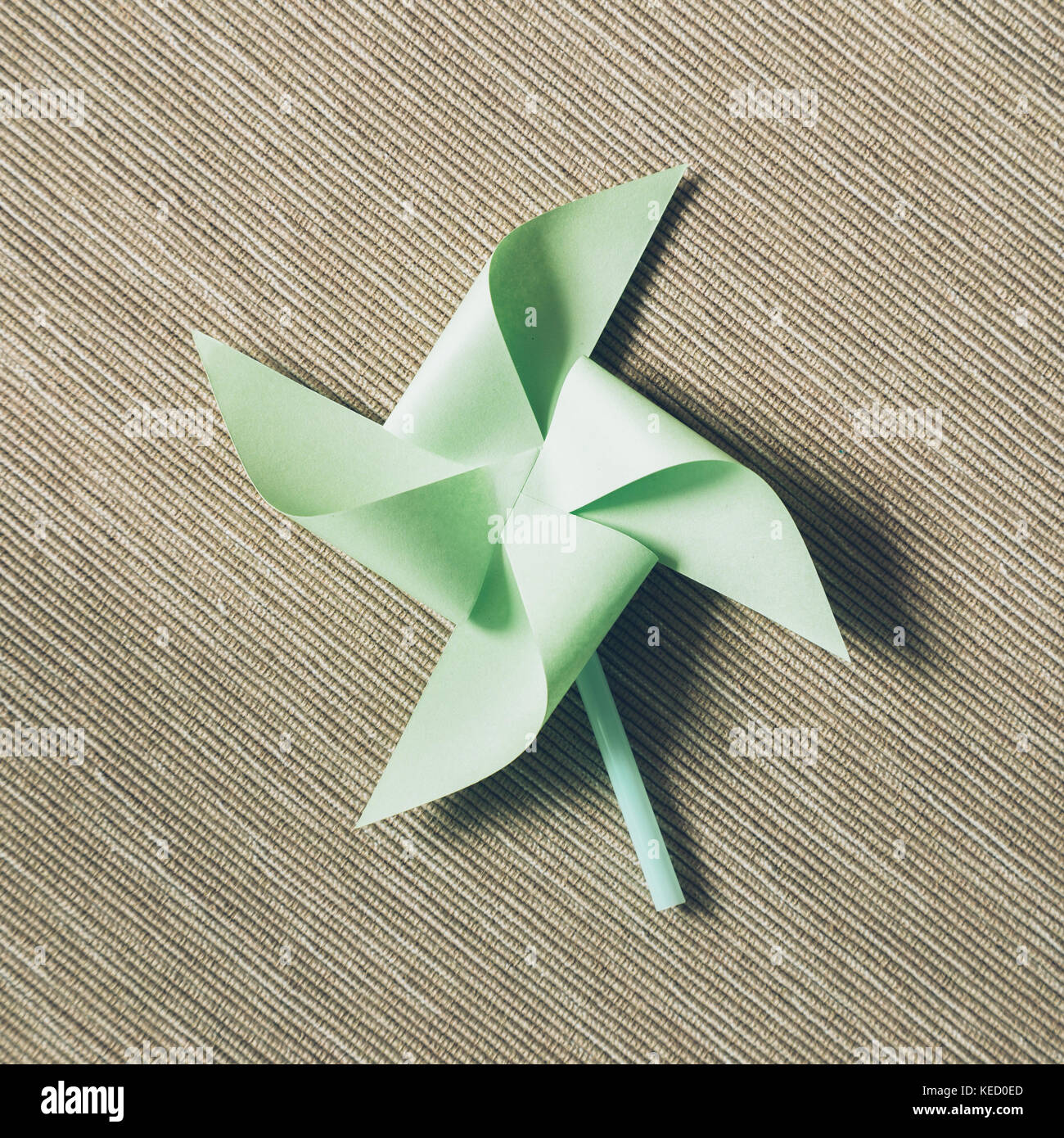Green paper pinwheel on brown fabric background Stock Photo - Alamy