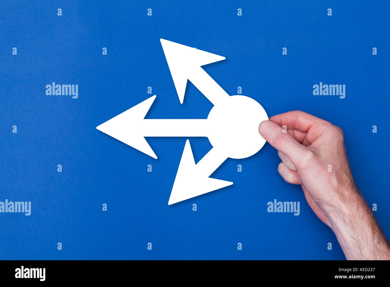 male hand holding an multi option arrow icon symbol against a blue ...