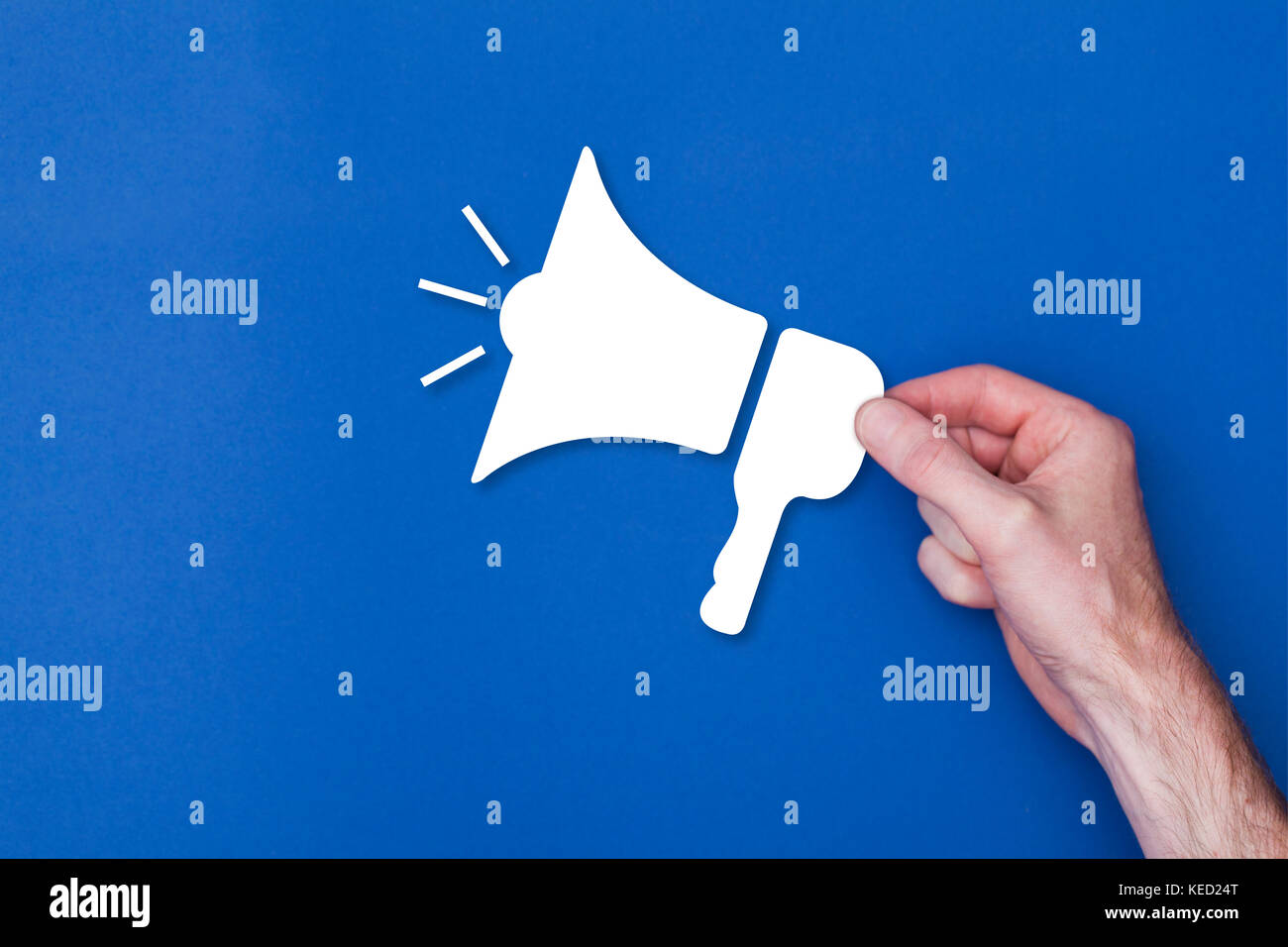 male hand holding a loud speaker icon symbol against a blue background ...