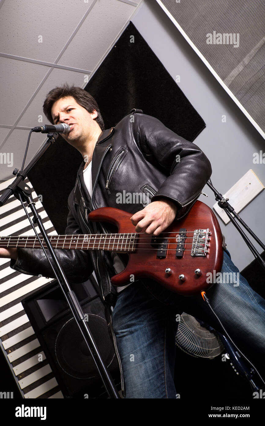 A Rock musician playing passionately bass in the rehearsal Studio Stock ...