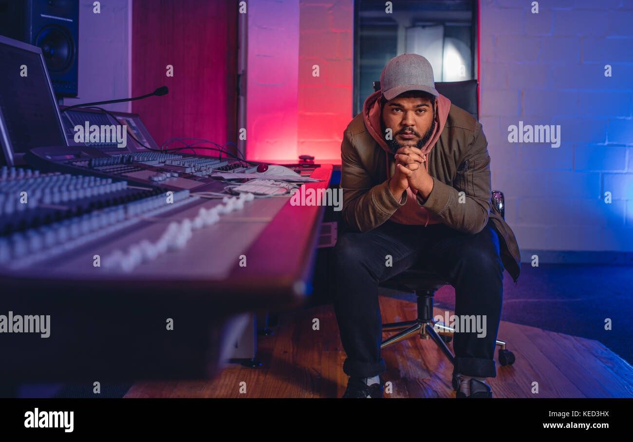 Young man sitting by audio mixing console in sound recording studio ...