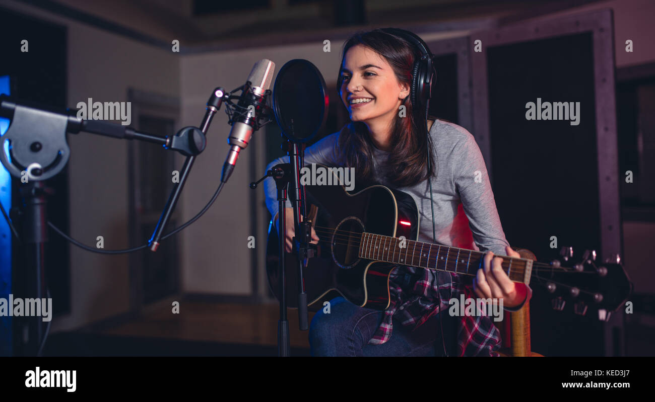 Happy young woman recording a song in a professional music studio ...