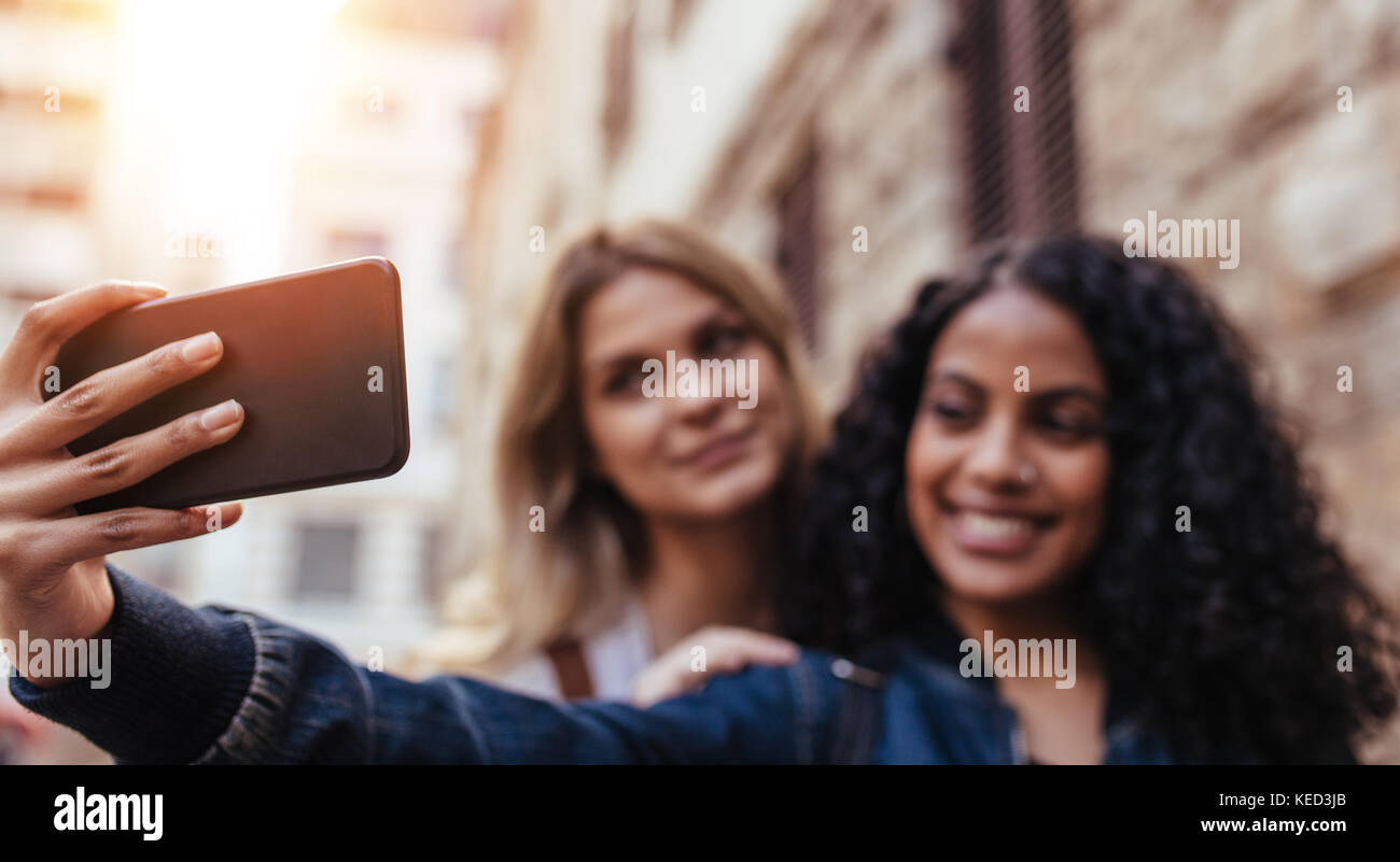 Girls clicking a selfie using mobile phone. Blurred image of women ...