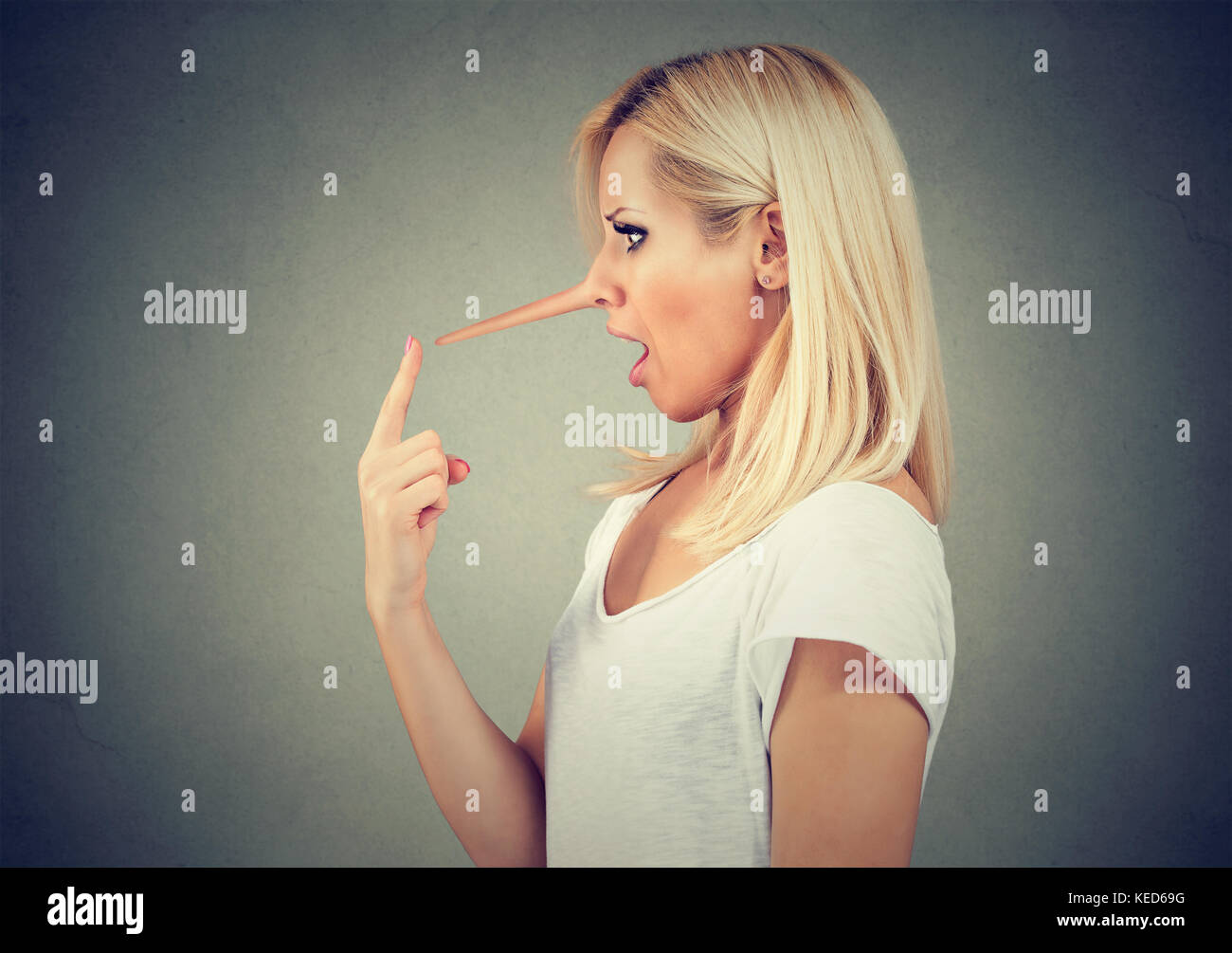 Surprised liar woman with long nose isolated on gray wall background ...