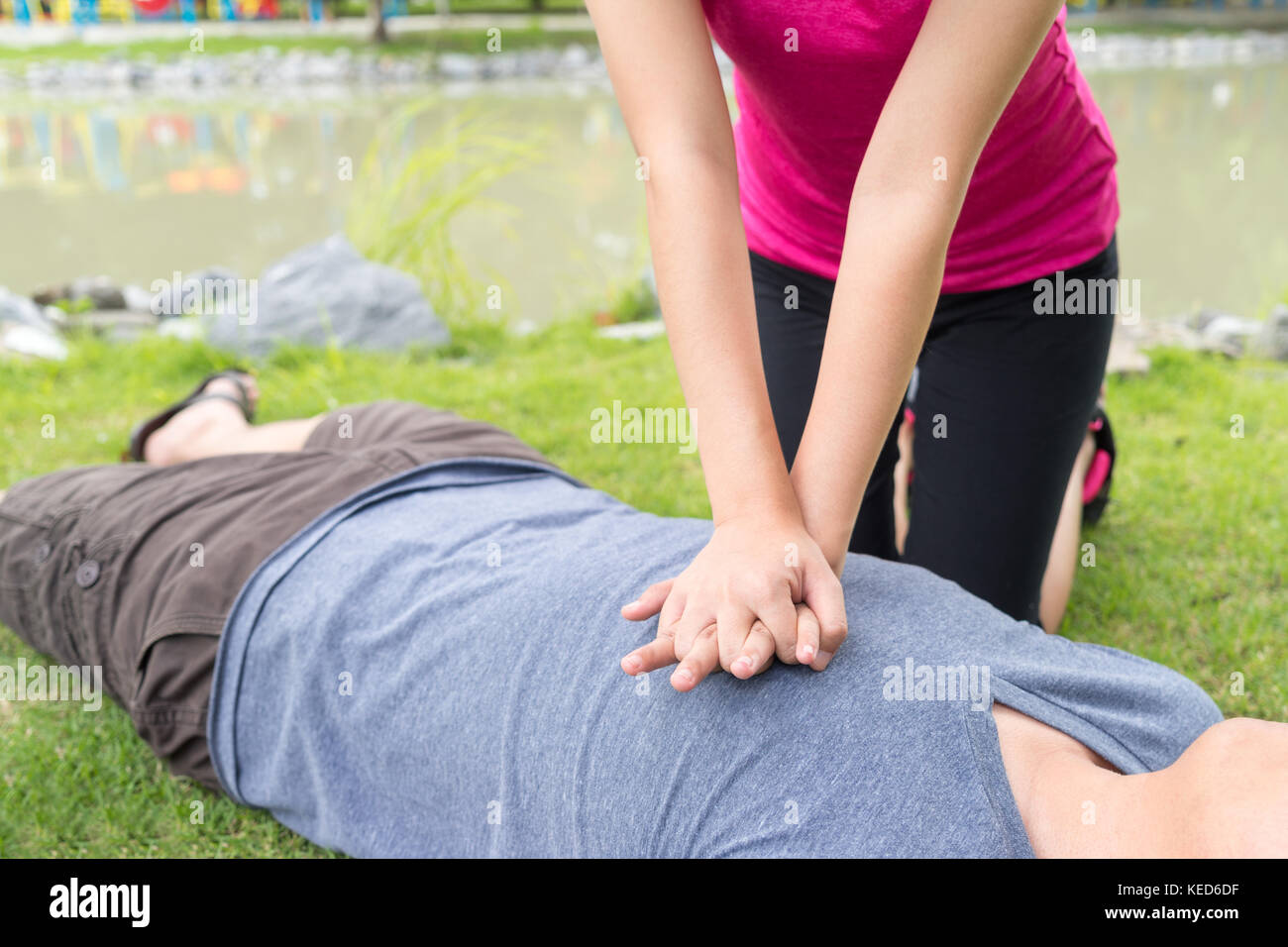 Woman giving cardiopulmonary resuscitation (CPR) to a man at public ...