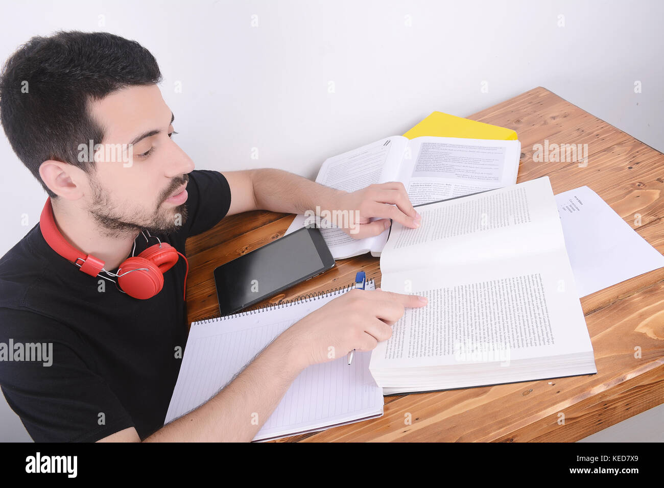 Attractive young man studying with digital tablet and books. Indoors ...