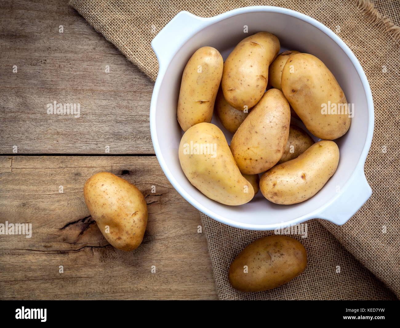 Composition of fresh organic potatoes in white ceramic bowl on hemp ...
