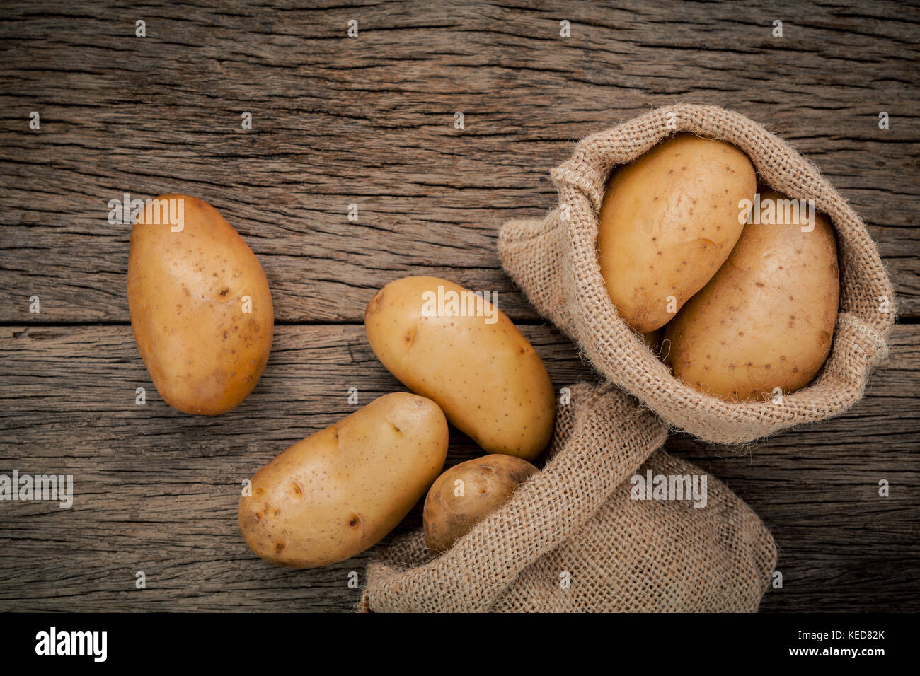 Fresh organic potatoes in hemp sake bags on rustic wooden background ...