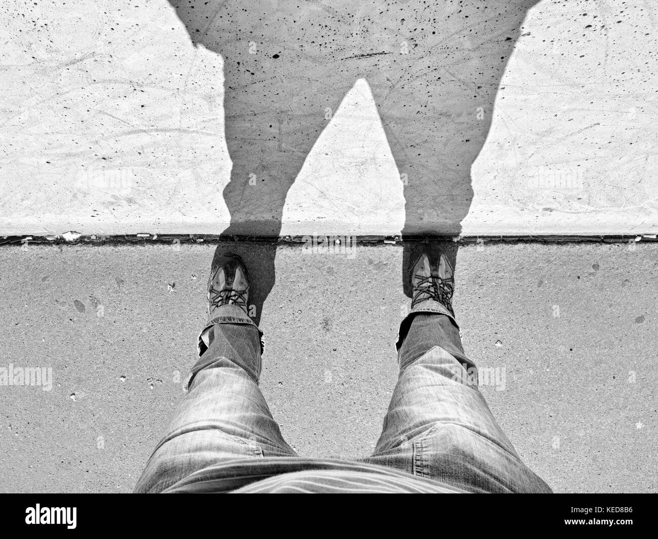 Man long legs stand on street at concrete wall with strong shadow ...