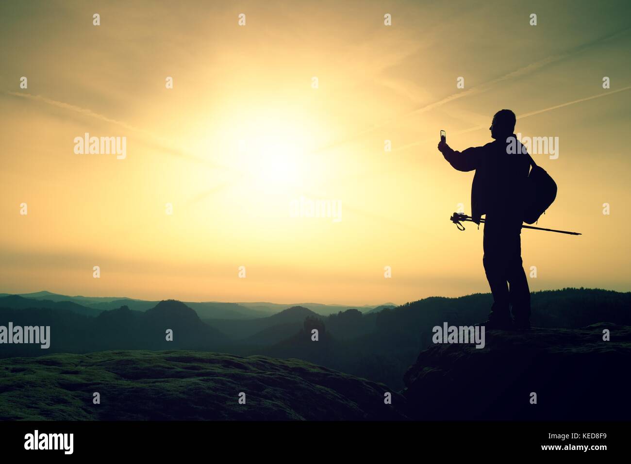 Strong man hiker taking photo with smart phone at mountain peak ...
