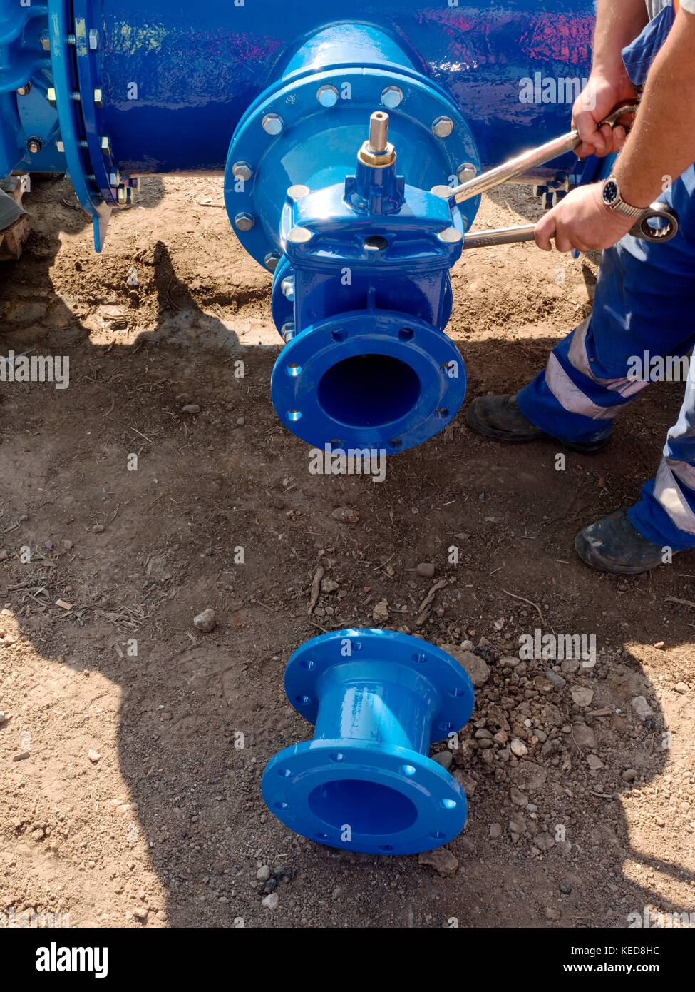 Worker hands with tools screwing nuts on new dring water piping. Piping ...