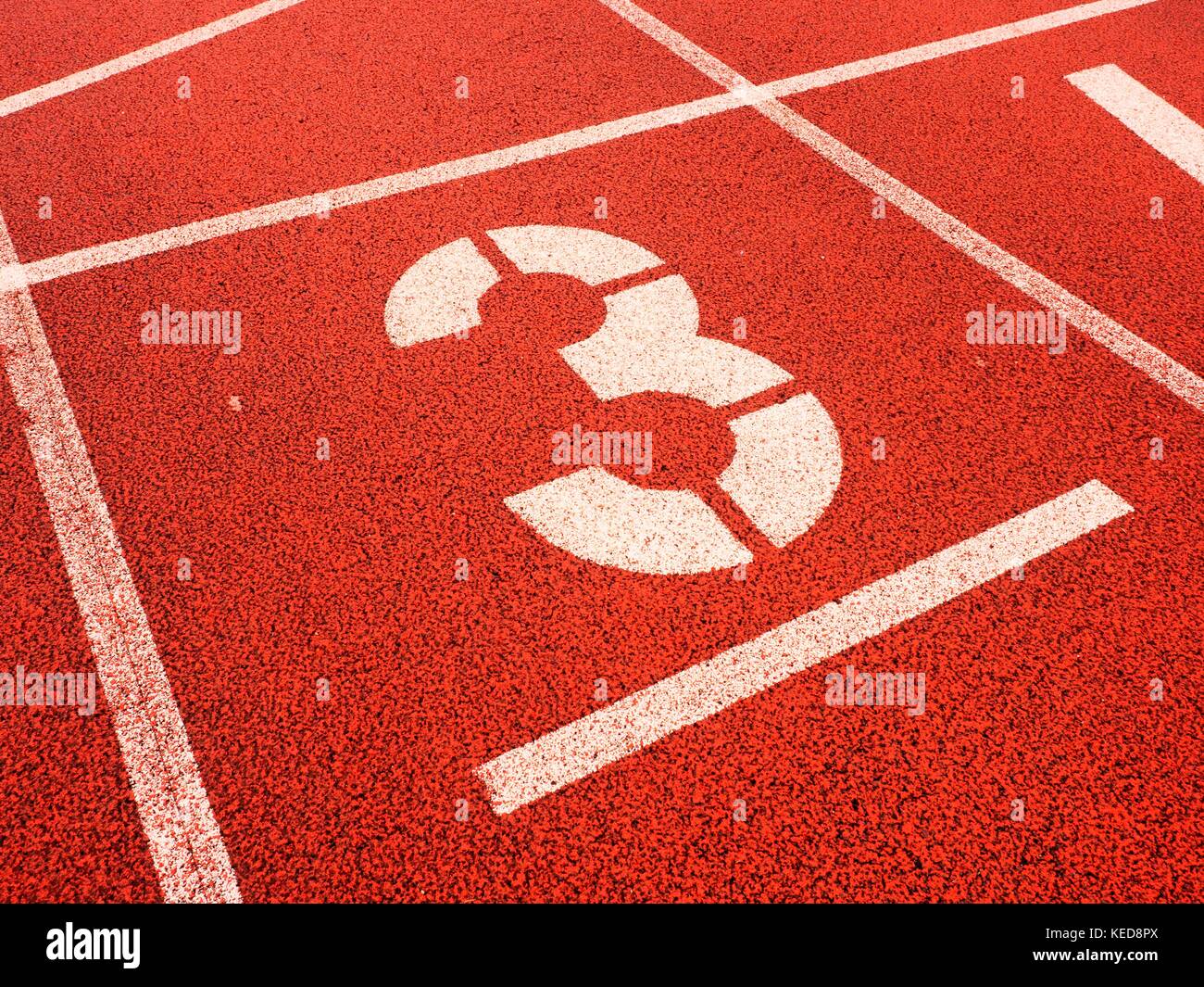 Number three. White track number on red rubber racetrack, texture of ...
