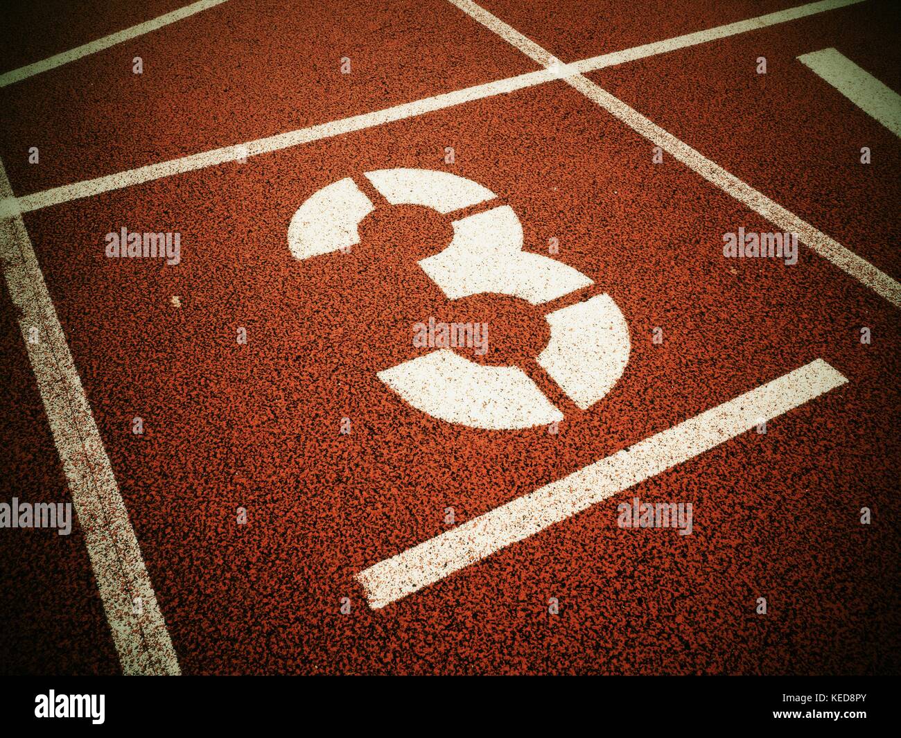 Number three. White track number on red rubber racetrack, texture of ...