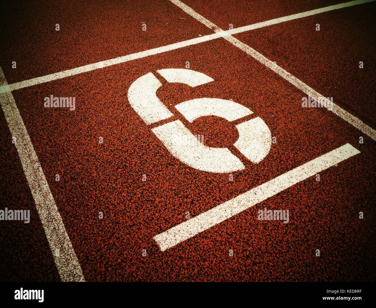 Number six. White athletic track number on red rubber racetrack ...