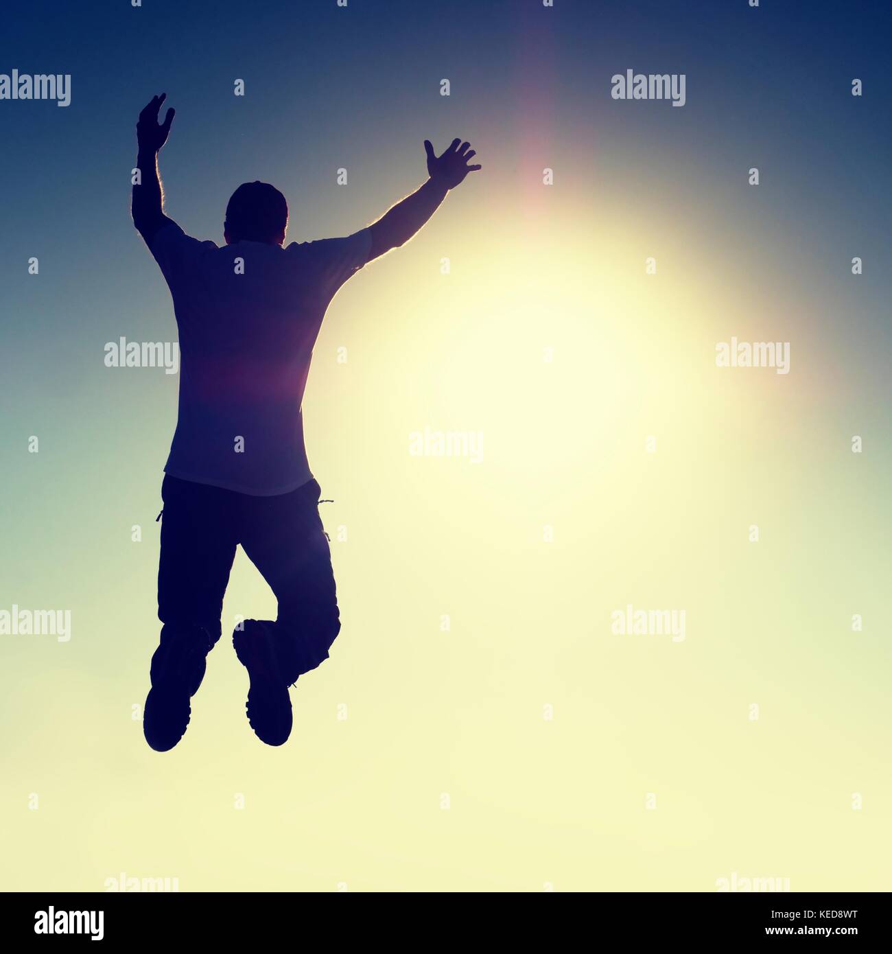Crazy man is flying over Sun on blue sky background. Silhouette of ...