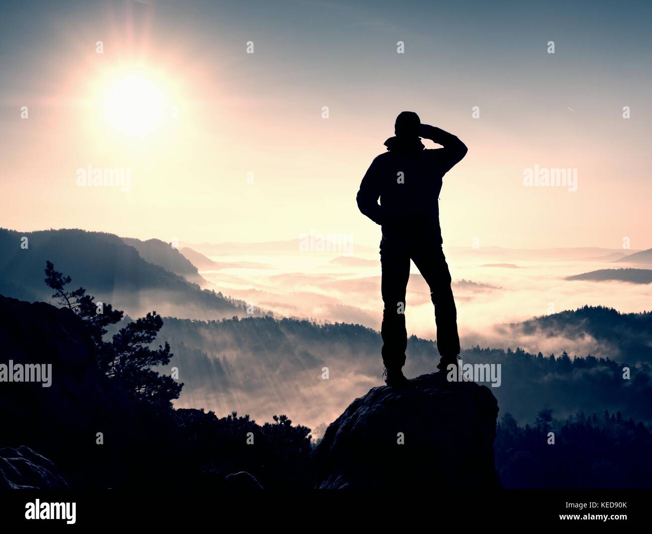 The man standing high on cliff. Hiker climbed up to rocky peak and ...