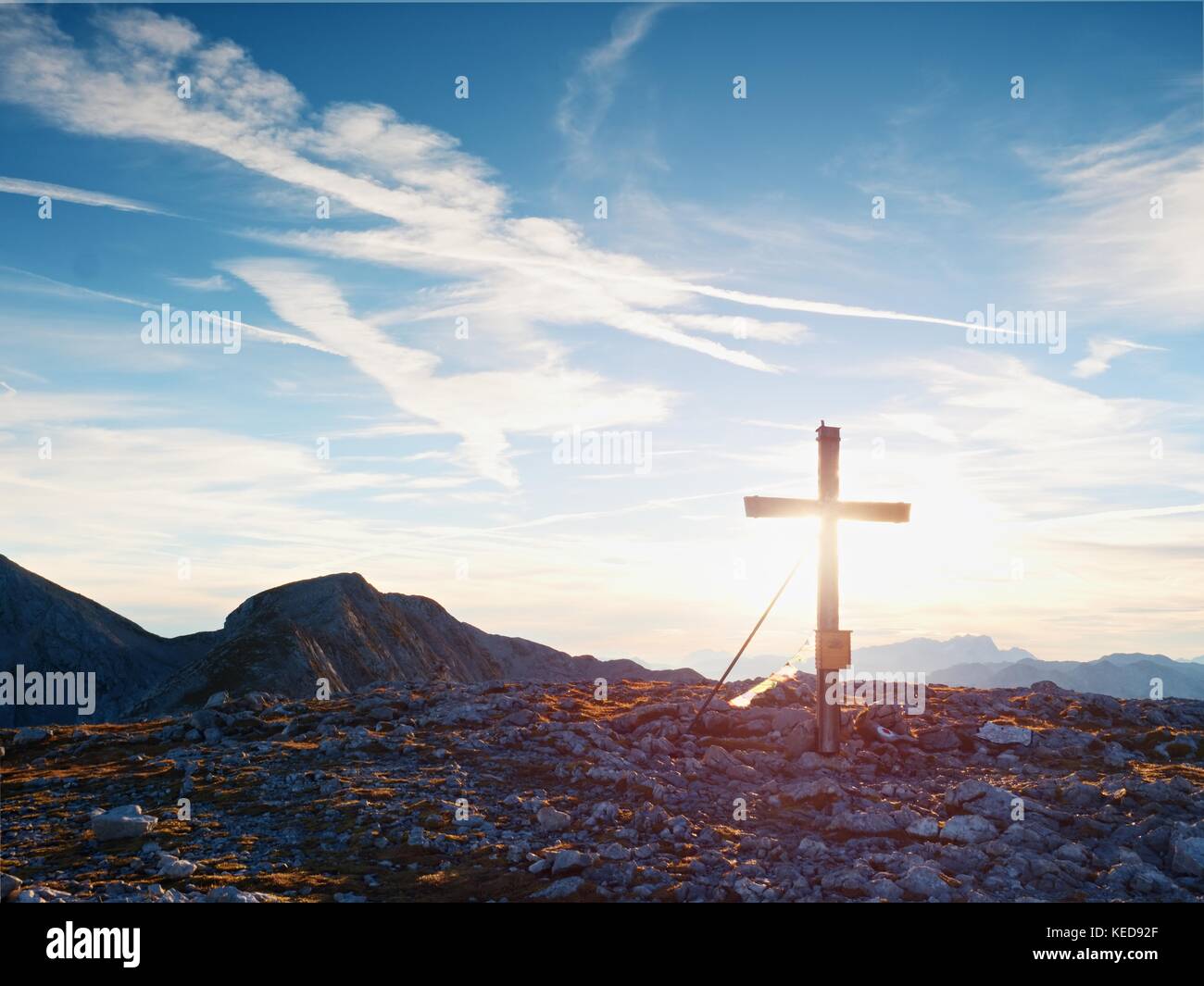 Modest wooden cross with Buddhist praying flags, raised on rocky Alpine ...