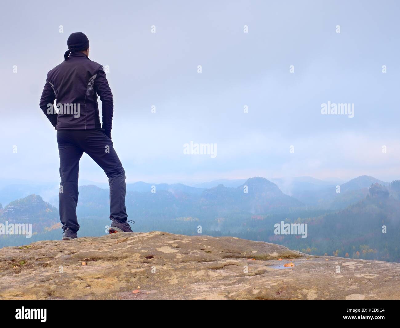 Foggy rocks. Hiker kin black on sharp cliff of sandstone rock in rock ...