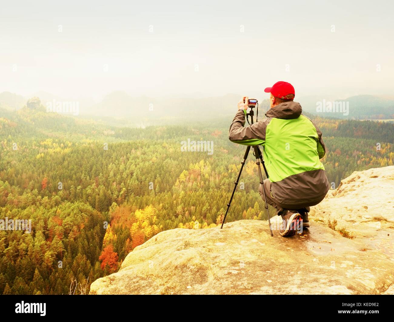 Nature photographer sit on rocky edge and takes photos with mirror ...