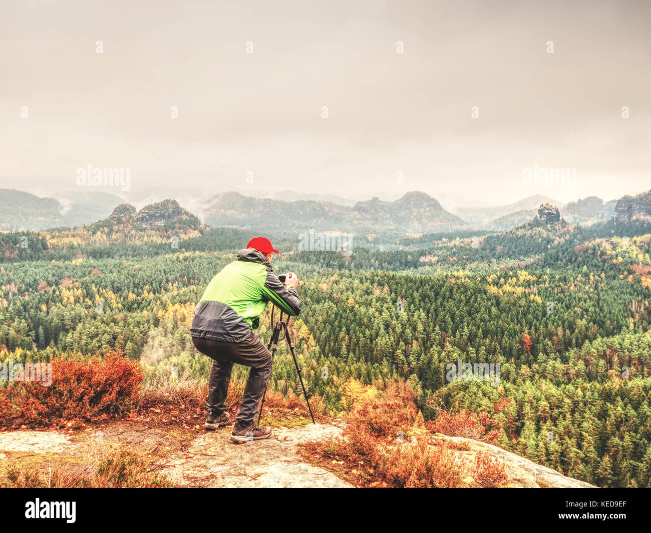 Nature photographer sit on rocky edge and takes photos with mirror ...