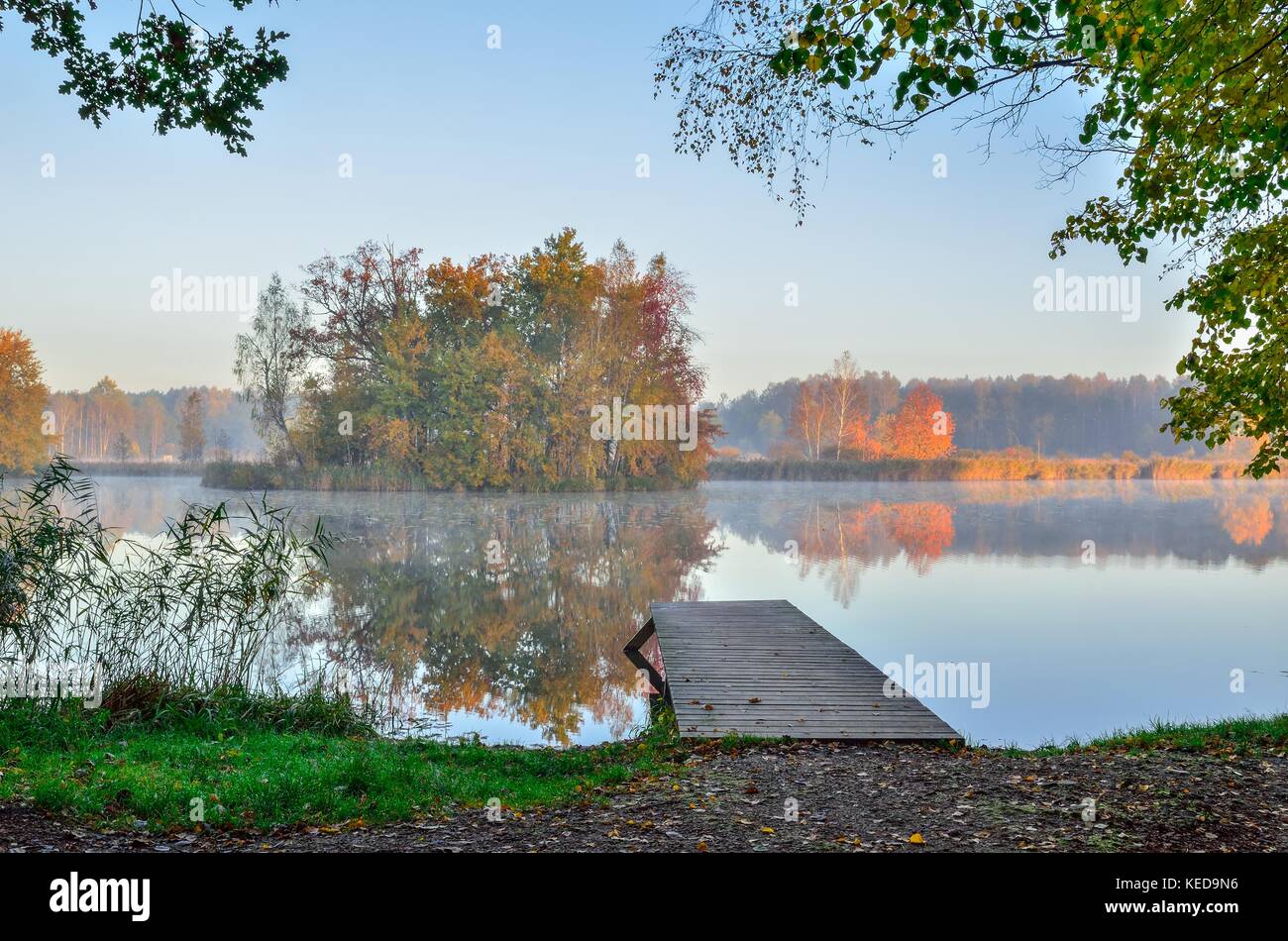 Beautiful autumn landscape. Wooden pier and island with trees on the ...