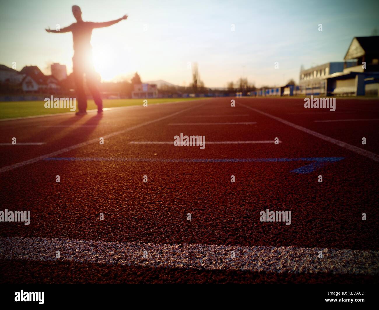 Tall man running on red running racetrack on the stadium. Sportsman in ...