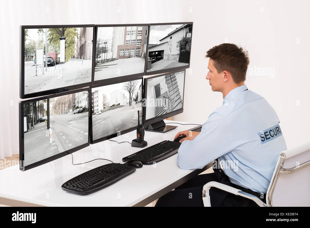 Rear View Of A Young Male Security Guard Monitoring Multiple CCTV ...