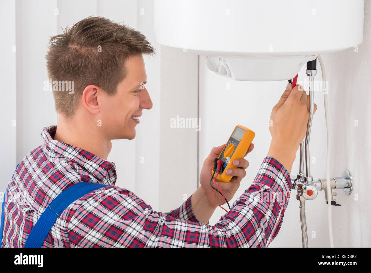 Smiling Male Plumber Examining Electric Boiler With Multimeter Probe ...