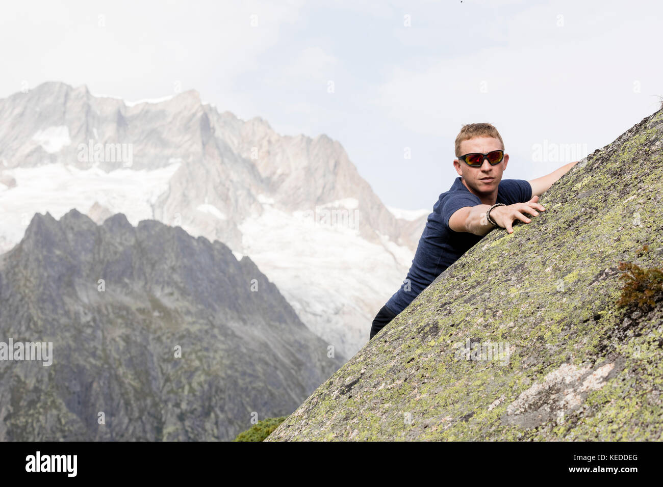 A climber makes climbing exercises on a big rock. In the background ...