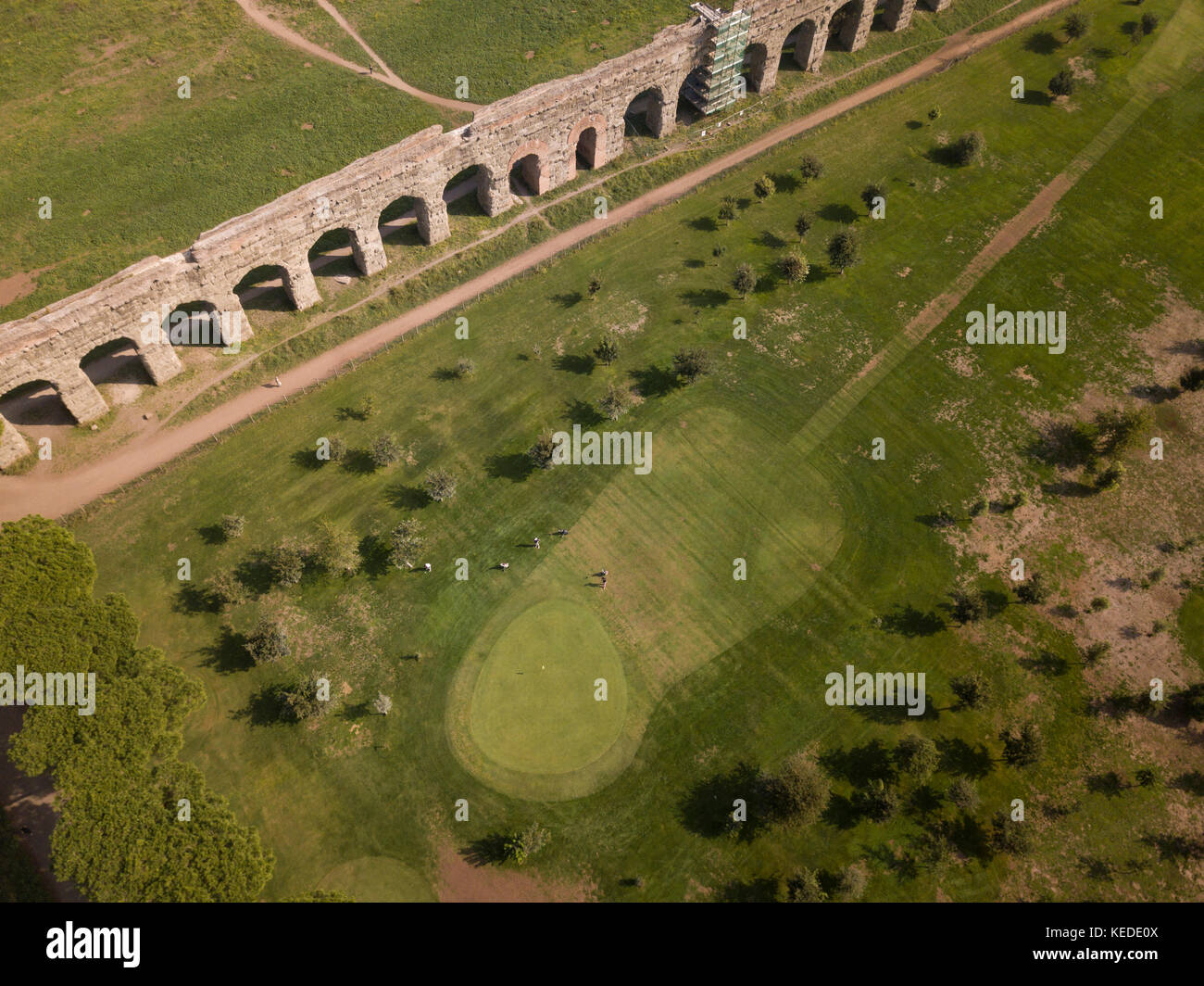 Aerial view of some people playing golf in a field near the ancient ...