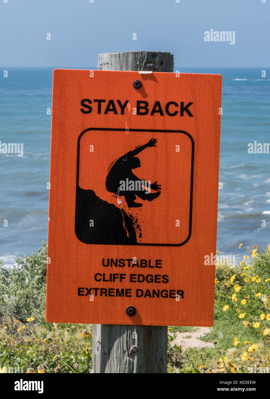 Unstable Cliffs Warning Sign on wooden post over cliff near ocean side ...